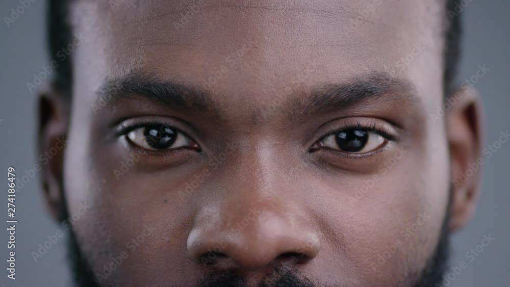 Close-up shot of young black man big eyes blinking and staring at ...