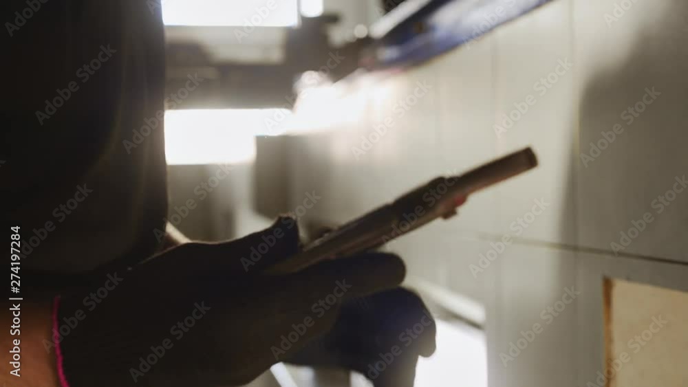 Mechanic stands in a car pit under lifted vehicle and prepares his ...