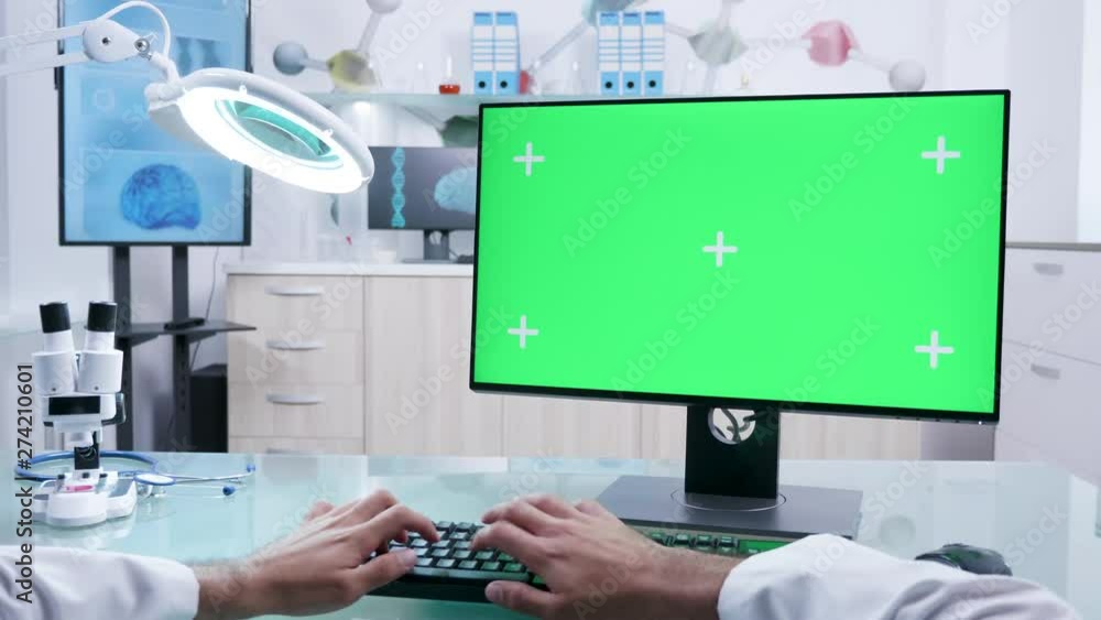 First person view of male doctor hands typing on computer with green ...