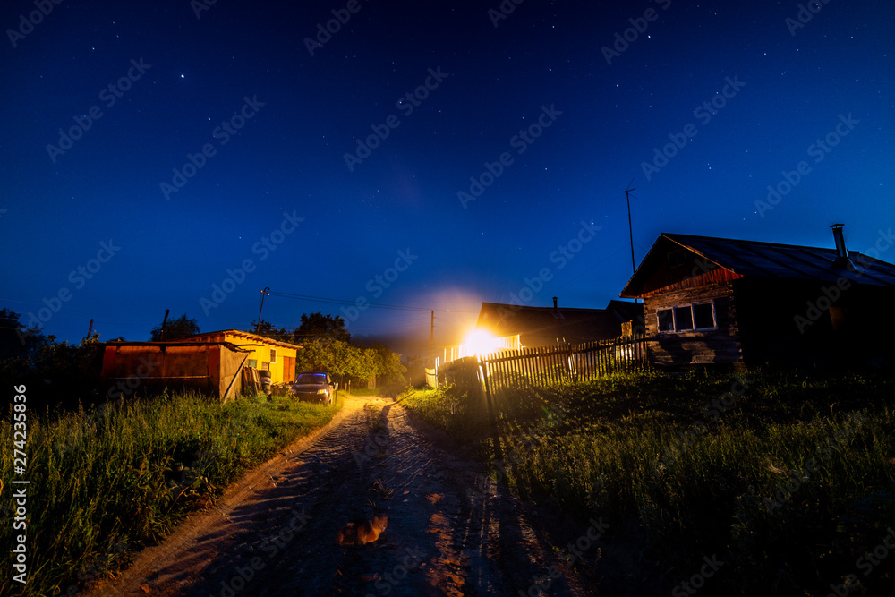Starry night sky over village house in summer. Wooden house with one ...