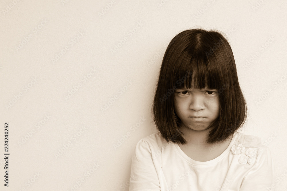 Angry little Asia kid in white shirt in cream wall background. Anger ...