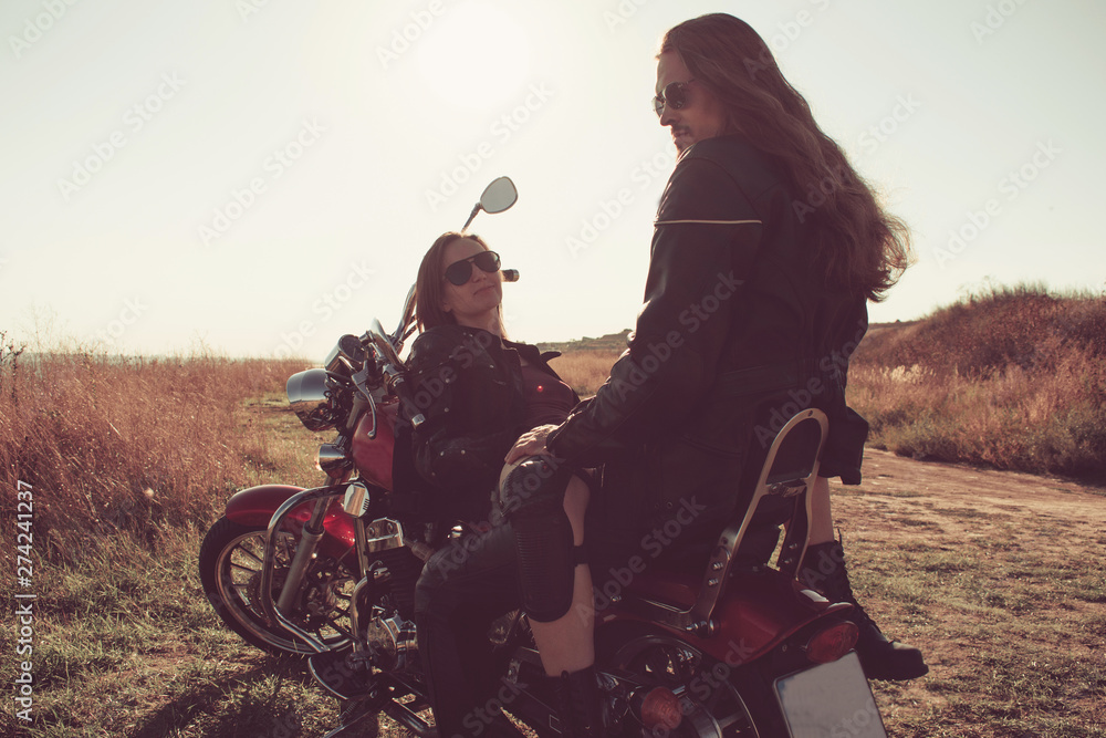 Romantic biker couple in leather on red motorcycle kissing and hugging ...