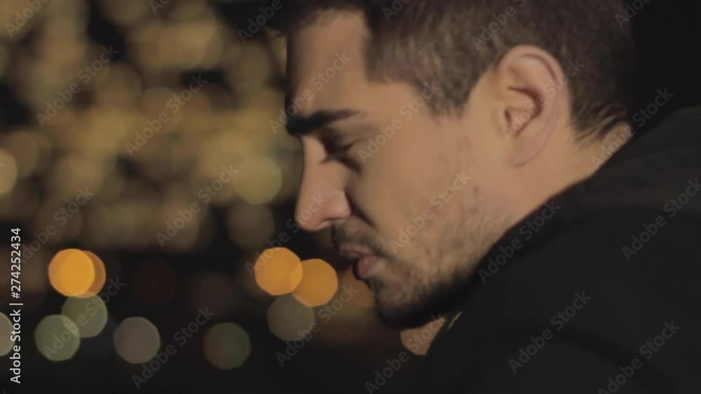 Sad handsome man with beard and brown hair leaning on a railing of the ...