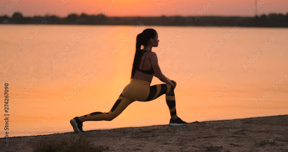 Woman is making lunges and crouching outdoors, training her body. Young ...