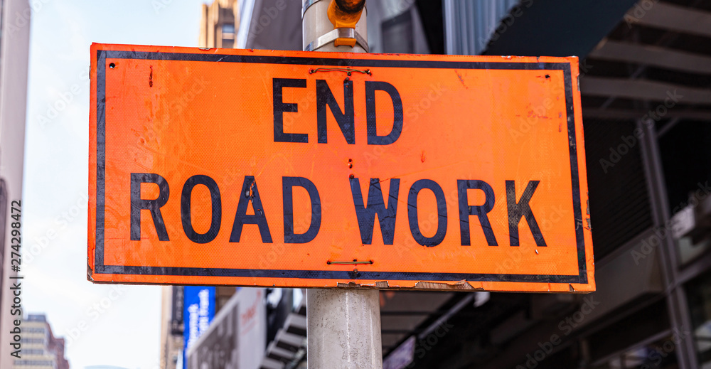 End Road Work. Warning sign, orange color, blur buildings background ...