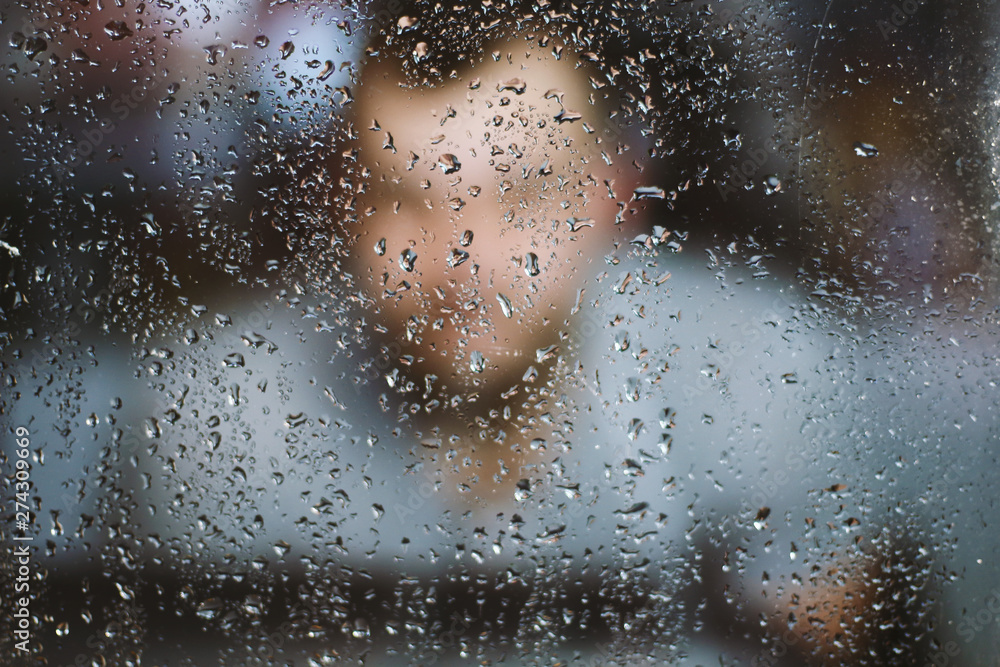Male man ghostly blurred silhouette through the window with raindrops ...