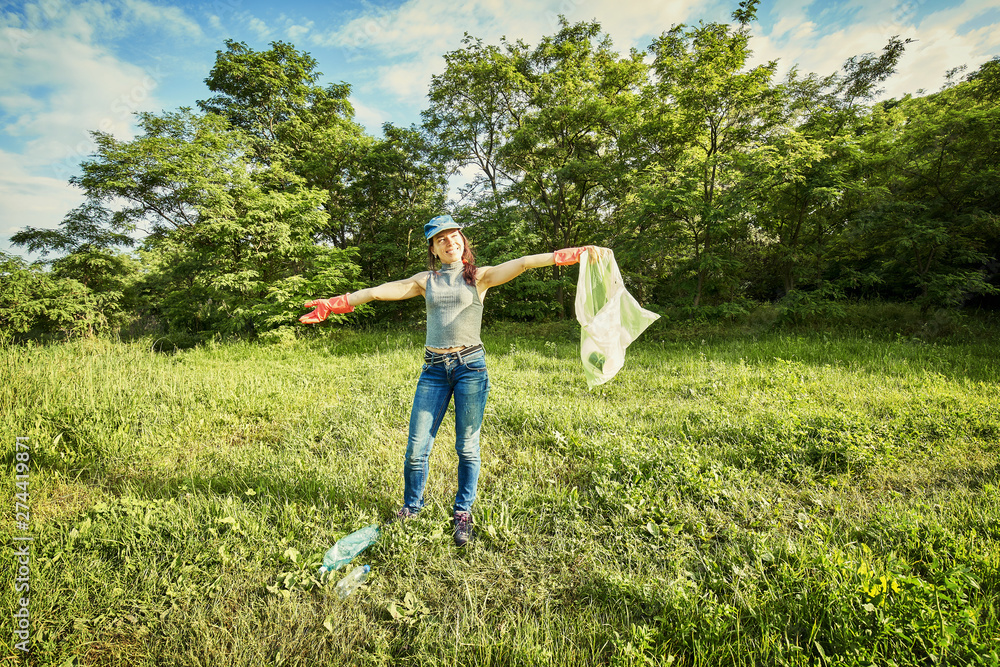 Young girl picking up the garbage and putting it in a garbage bag on a ...