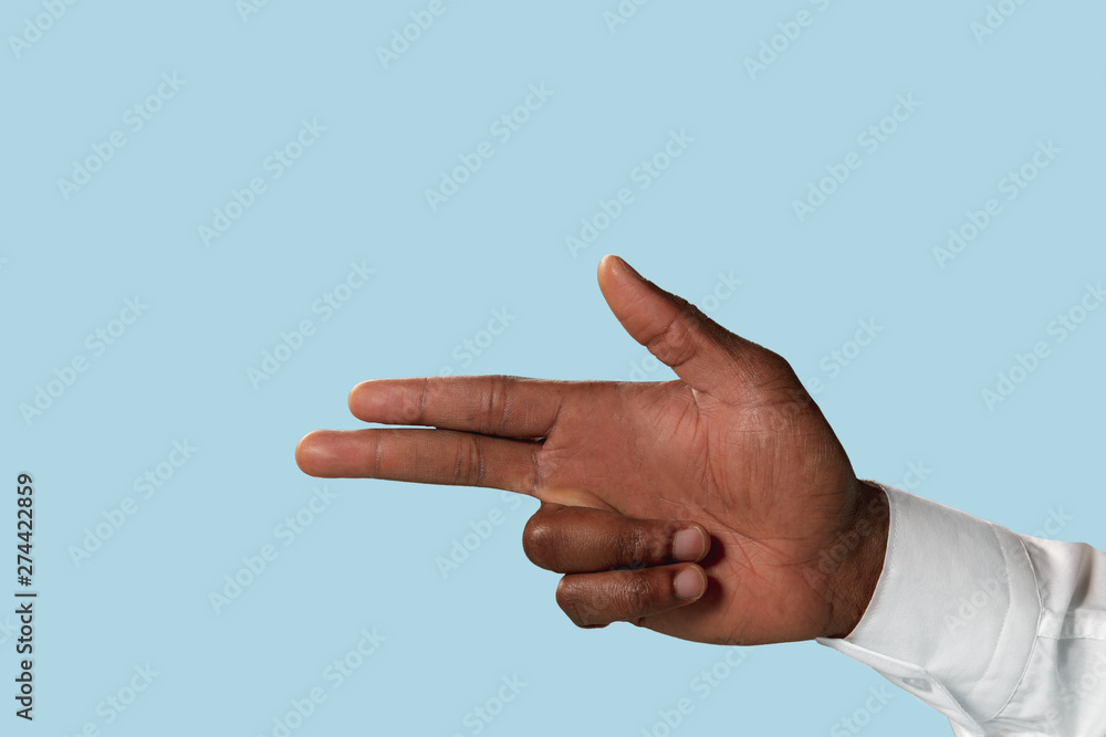 Male hand in white shirt demonstrating a gesture of gun, handgun or ...