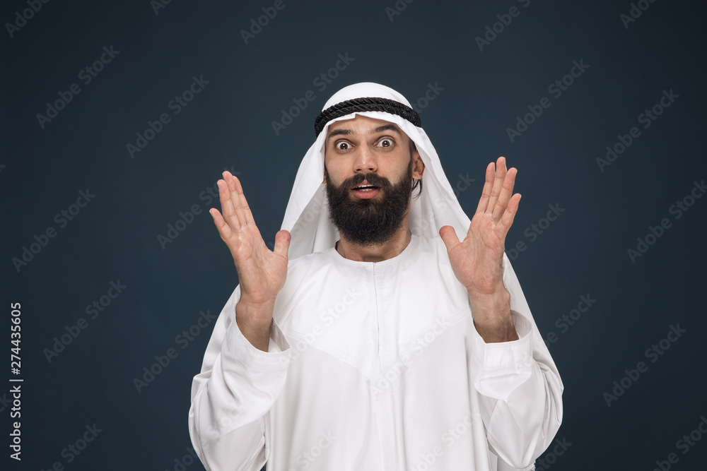 Portrait of arabian saudi businessman on dark blue studio background ...