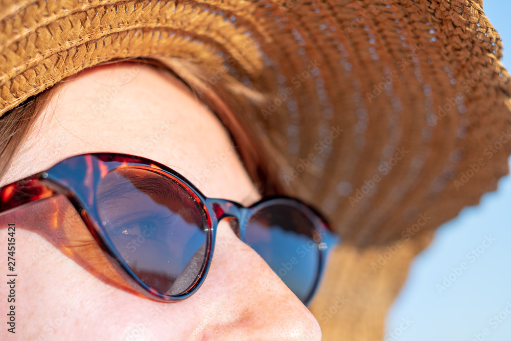 Young woman wearing a summer hat and sunglasses, close-up portrait ...