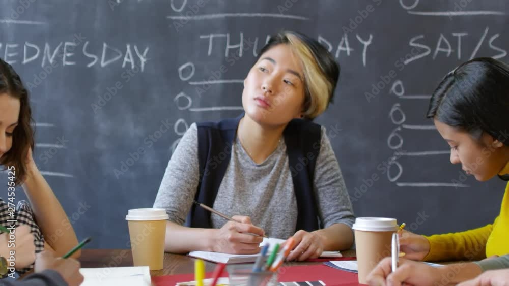 Dollying chest-up shot of 20-something Asian designer sitting around ...