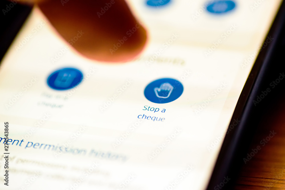 Stop a cheque button on smartphone app screen closeup with human finger ...