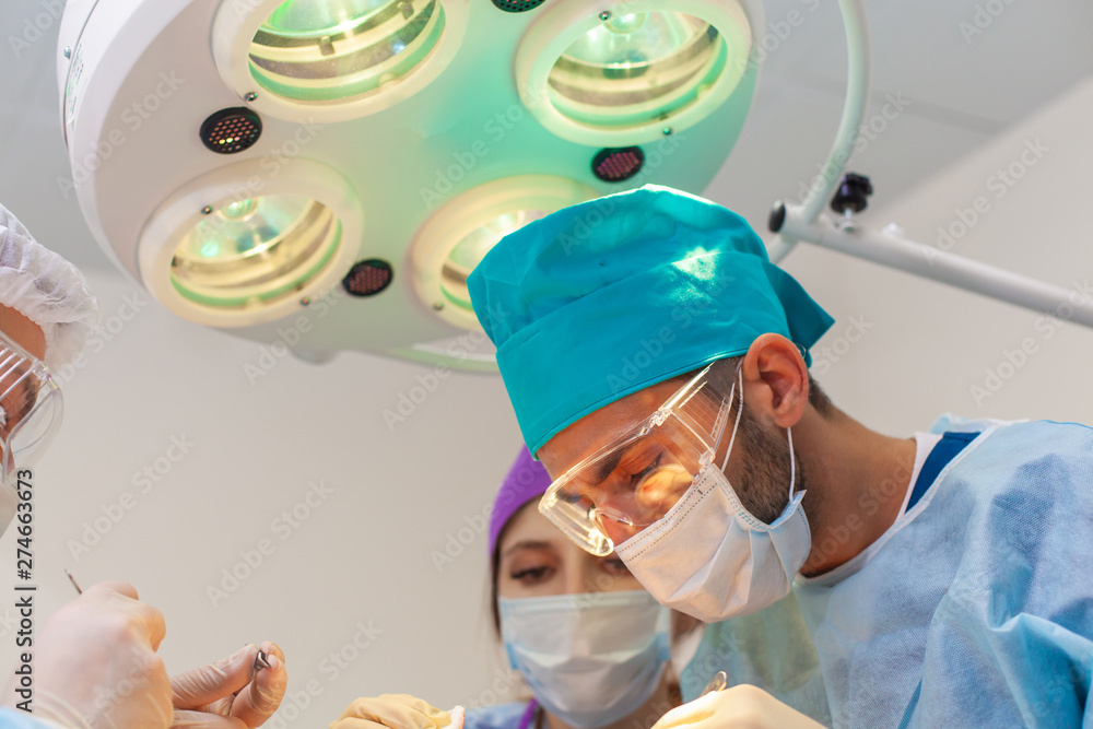 Baldness treatment. Hair transplant. Surgeons in the operating room ...