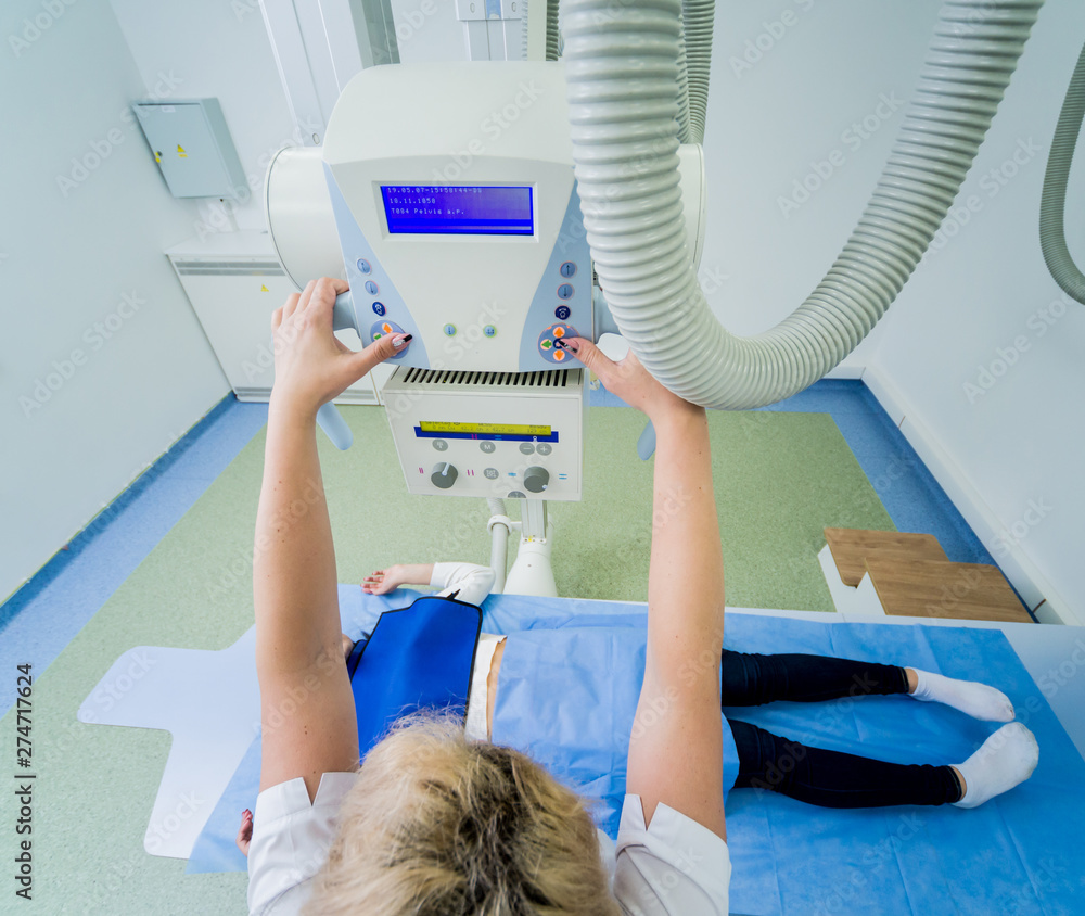 Radiologist and patient in a x-ray room. Classic ceiling-mounted x-ray ...