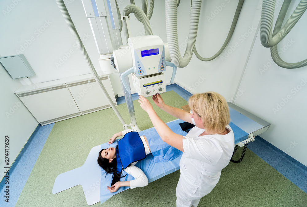 Radiologist and patient in a x-ray room. Classic ceiling-mounted x-ray ...