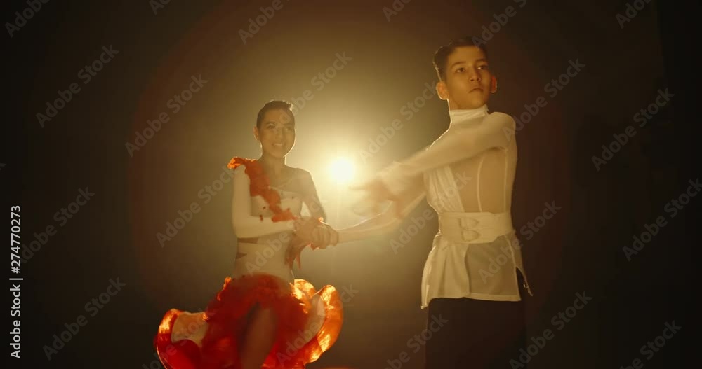 Teen asian kids performing ballroom sport dance on stage with smoked ...