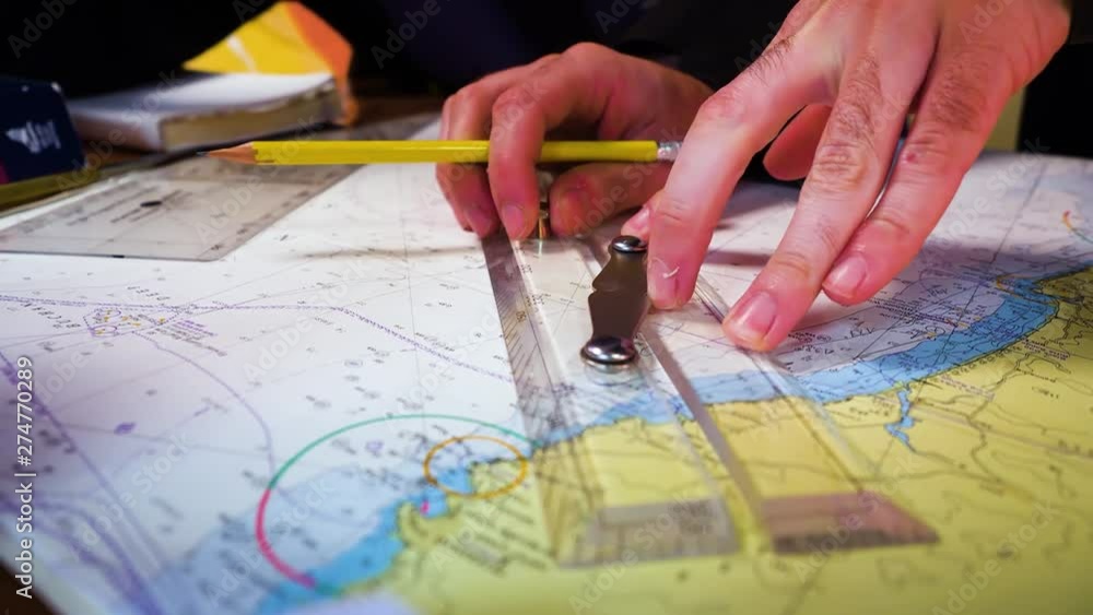 Yachts navigator using a parallel ruler and pencil while plotting a ...