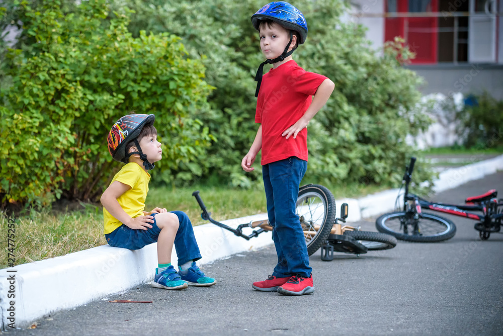 little boy fallen off of his bike. Unhappy boy sitting on asphalt ...
