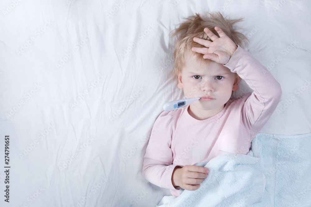 The sick girl, the child with the thermometer in a mouth, on a bed, the ...