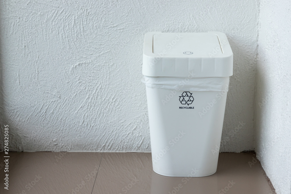 white plastic trash bin on floor of living room. indoor recycle bin at ...