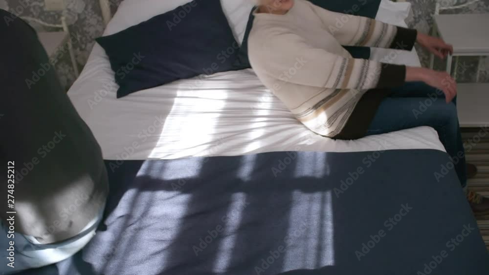 Top shot of double bed in hotel room, mature Caucasian man and woman ...