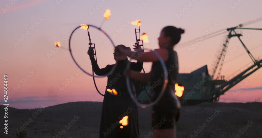 Fire dancers against sunset. A young woman poses with her fire hoop ...