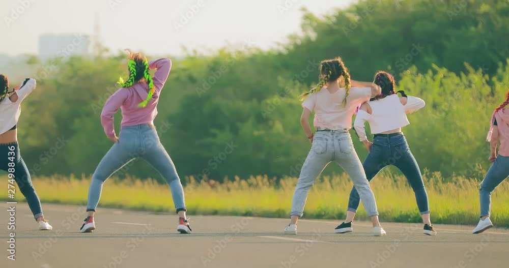 Hip-hop dance in nature in the summer. Stylish girls in jeans are ...