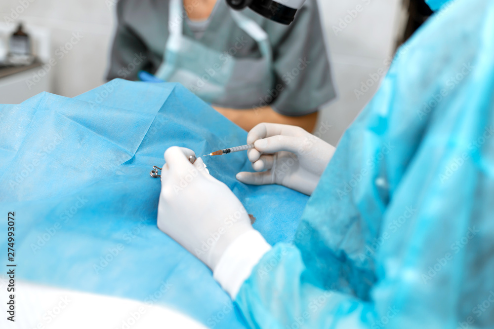 A professional ophthalmologist performs eye surgery with a microscope ...