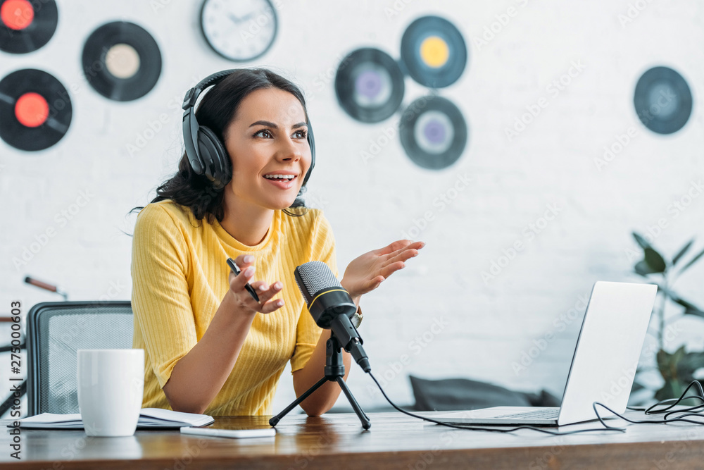smiling radio host gesturing while recording podcast in broadcasting ...