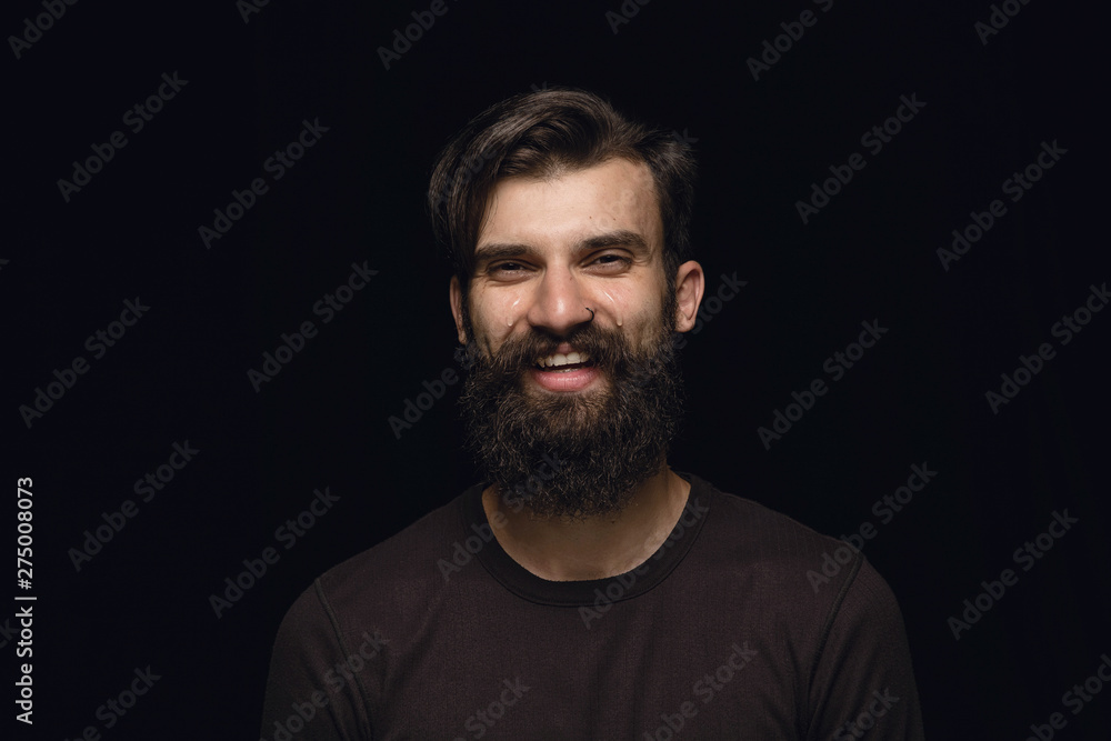 Close up portrait of young man isolated on black studio background ...