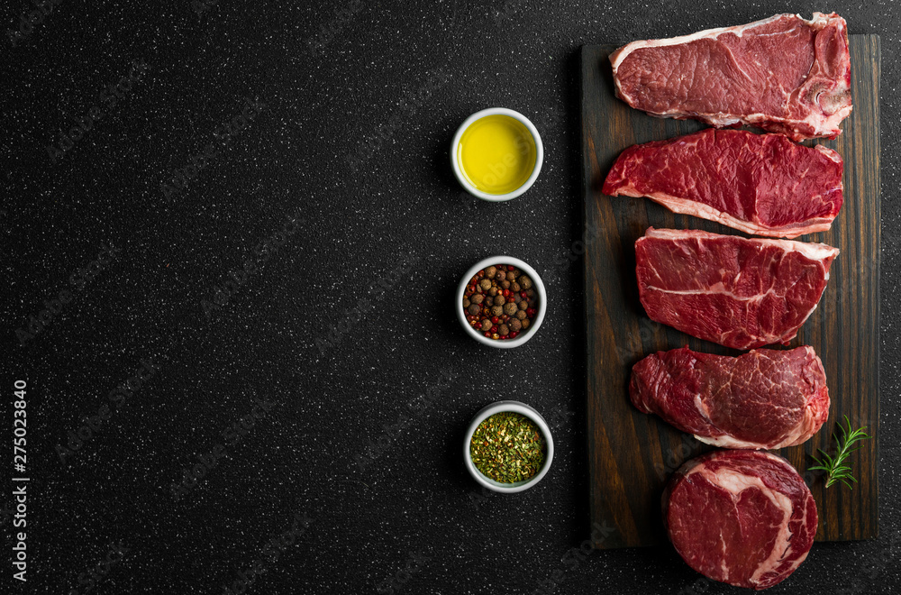 Selection of raw beef meat food steaks against black stone background ...