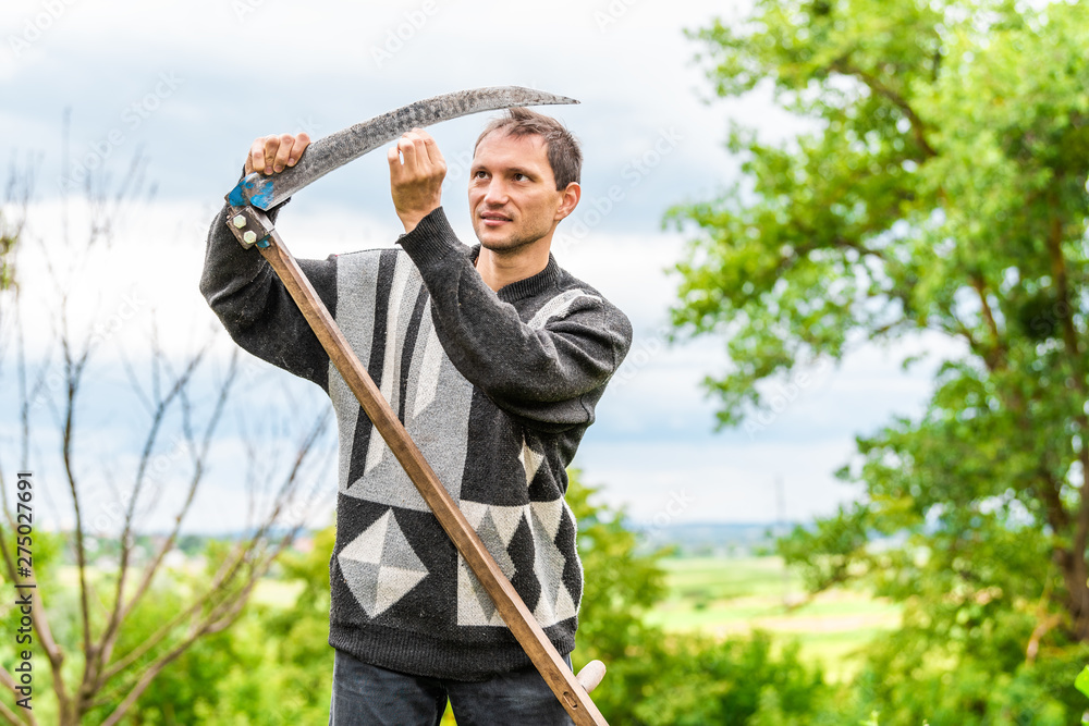 Happy man farmer in garden standing sharpening sickle scythe rake tool ...