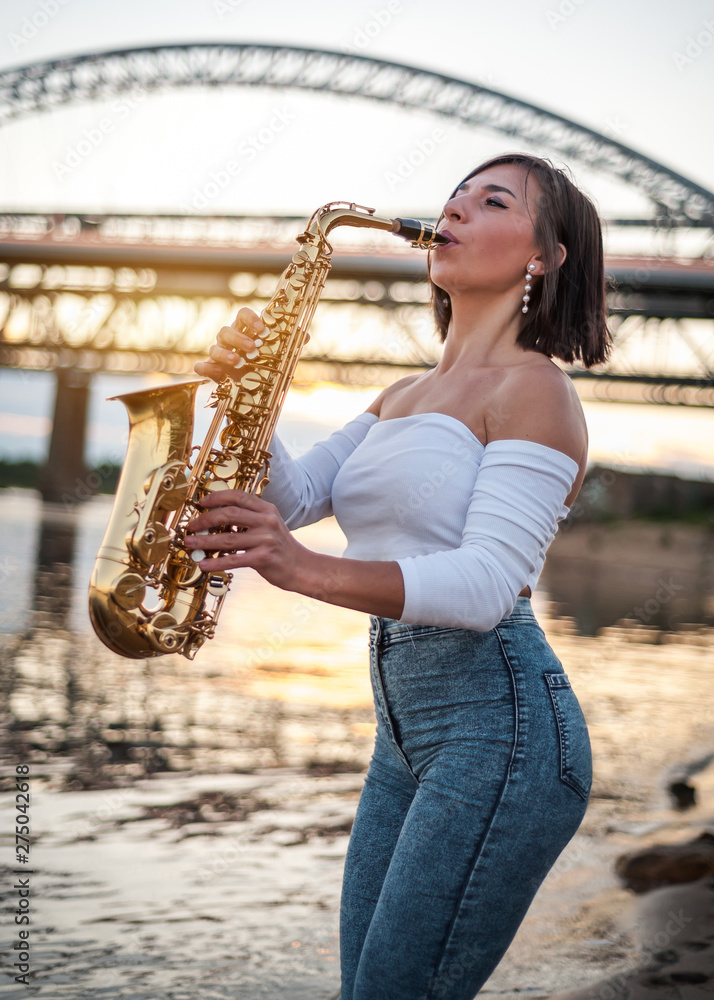 Woman playing the saxophone at sunset Stock Photo | Adobe Stock