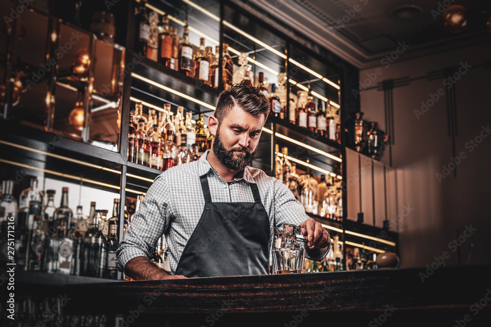 Happy smiling barman is prepairing drinks for customers at posh bar ...