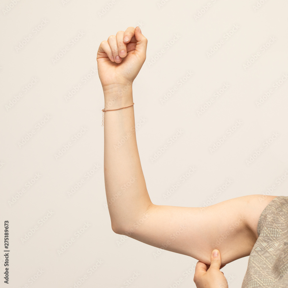 A closeup view of a young Caucasian lady squeezing her upper arm ...