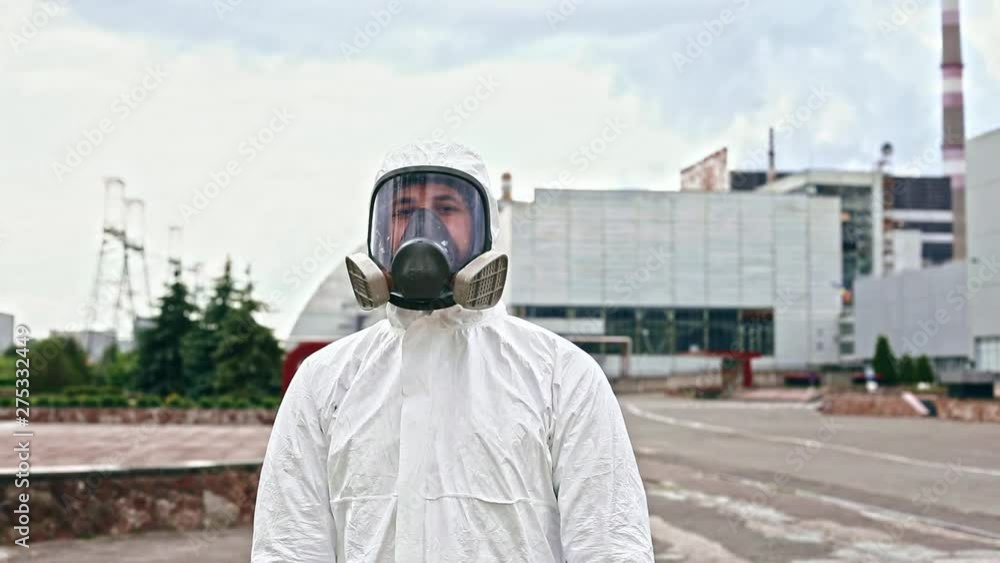 Portrait of curious young man in respirator and protective costume ...