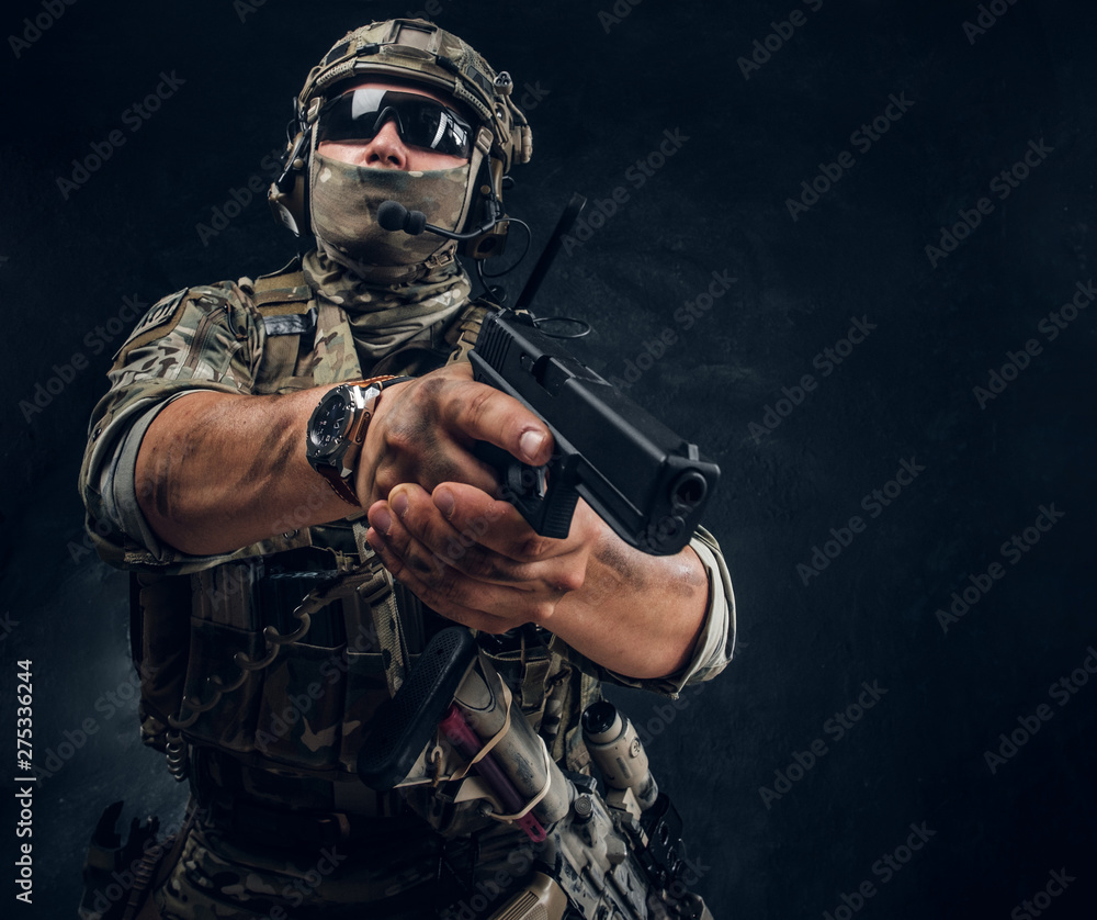 Serious brave soldier in military uniform and sunglasses is aiming with ...