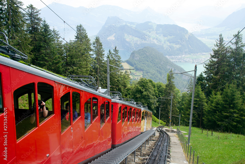 Red panoramic train on the background of the Alps and mountain lakes. A ...
