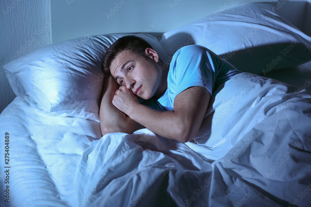 Young man suffering from insomnia while lying in bed at night Stock ...