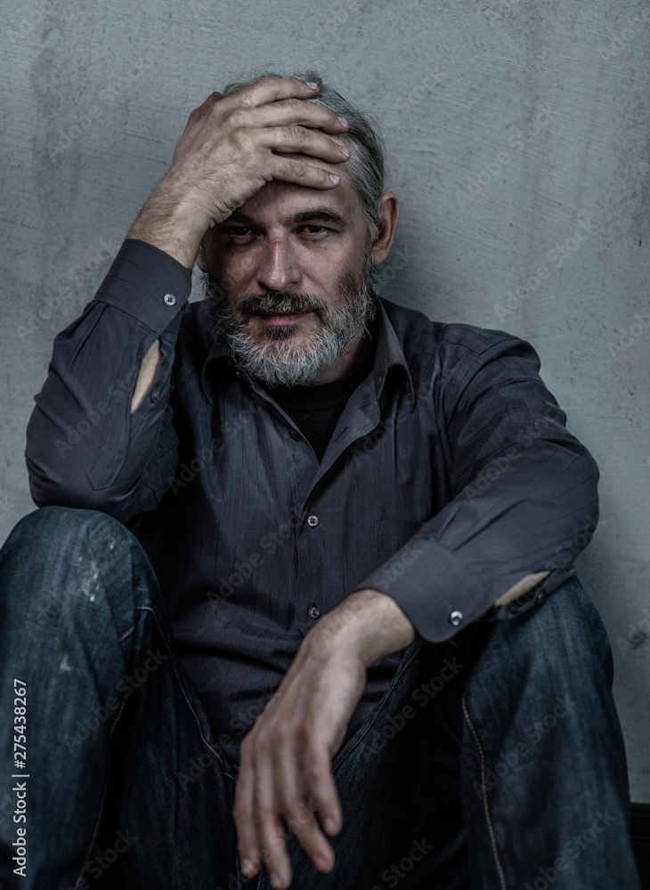 Portrait of a homeless man with a gray hair on dark background. Empty ...