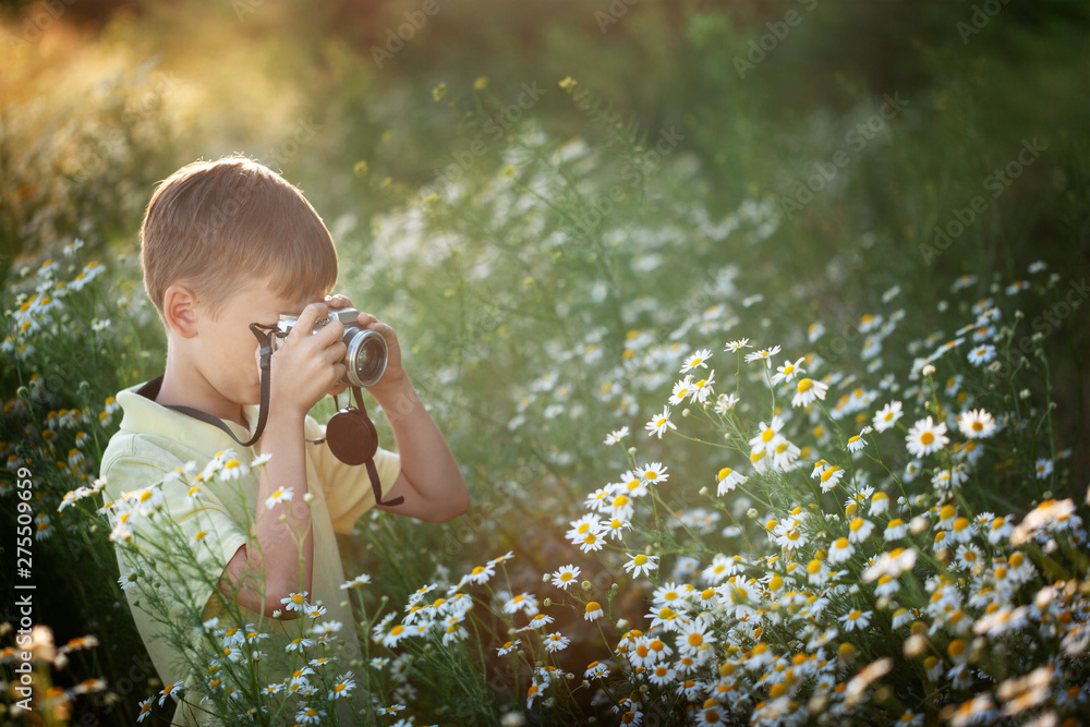 Cute boy photographer shoots on camera in nature. Kid takes a photo in ...