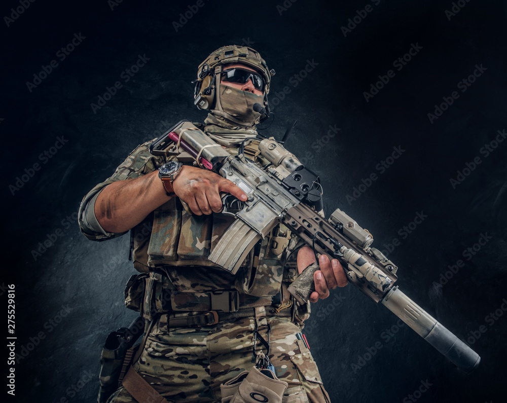 Military man in full equipment with wach on his hand is holding machine ...