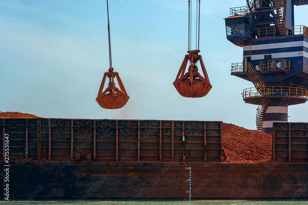 Loading bauxite ore on cargo ship with crane and bucket. Shipment from ...