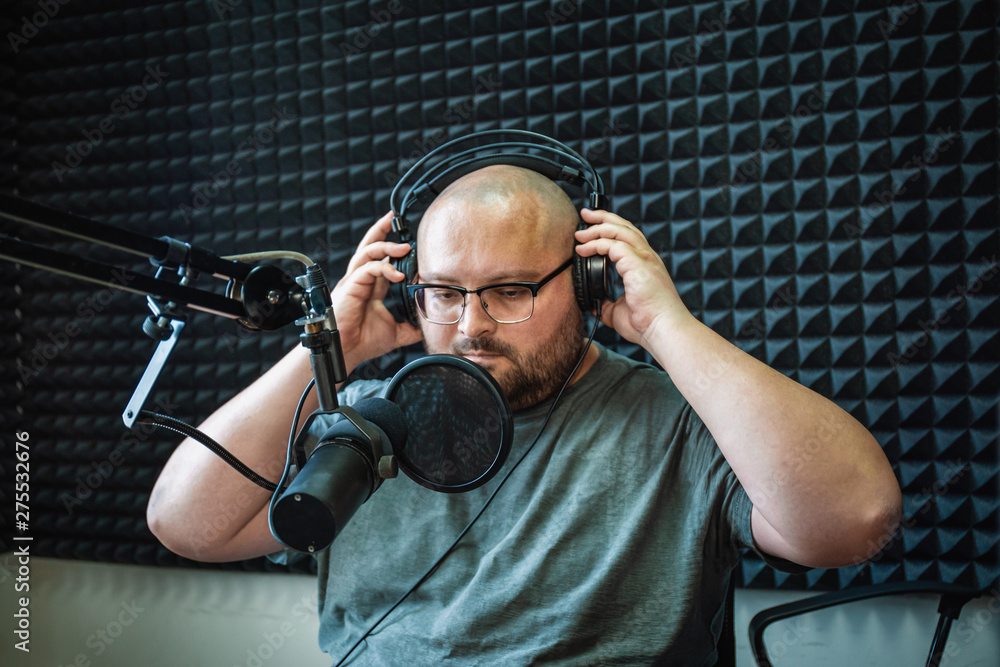 Fat radio presenter or host in radio station studio with headphones and ...