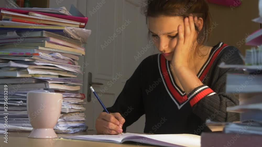 Static shot of a young pretty lady sitting on a desk with a pile of ...