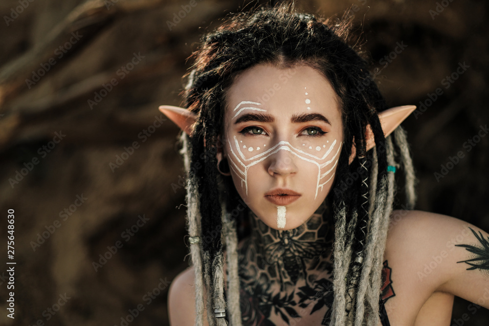 Beautiful young woman with elf ears, dreadlocks and an ethnic poncho ...
