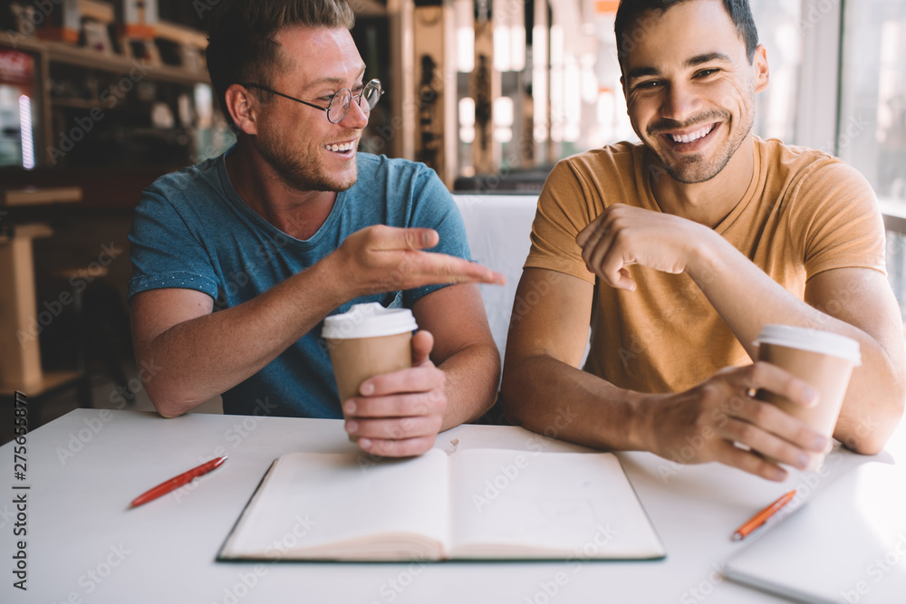 Excited hipster guys in casual wear enjoying collaboration in coffee ...