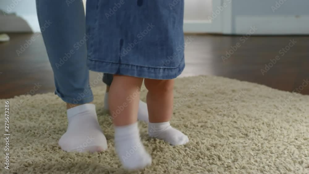 Vidéo Stock Close-up legs shot of baby girl making unsteady first steps ...