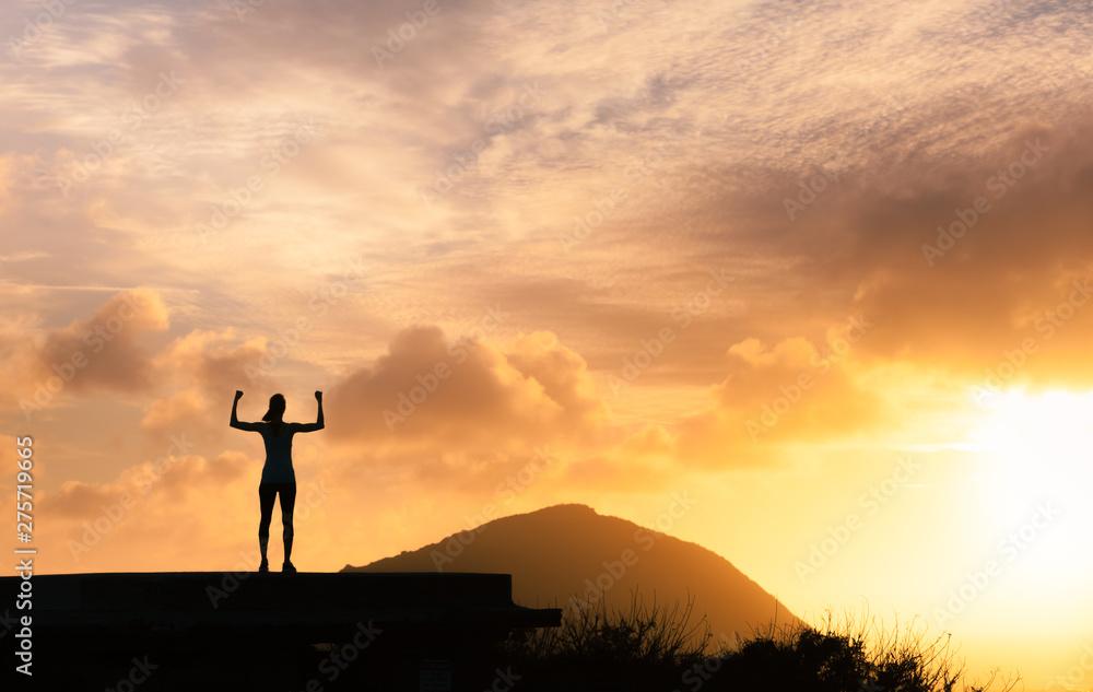 Strong victorious woman standing on top of mountain flexing her muscle ...