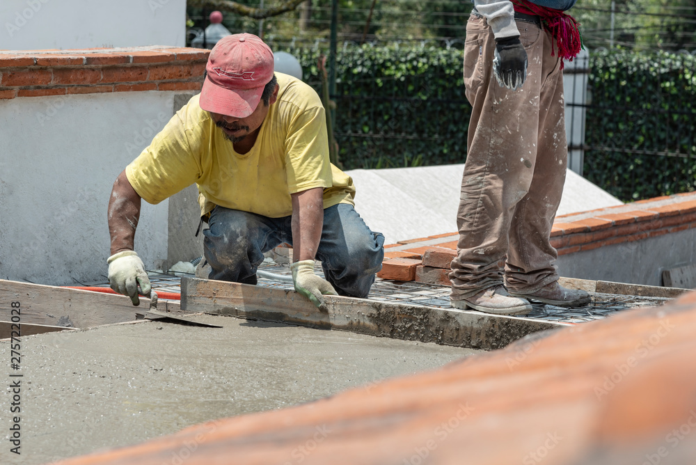 Bricklayer leveling a cement roof. Stretching out to smooth the casted ...